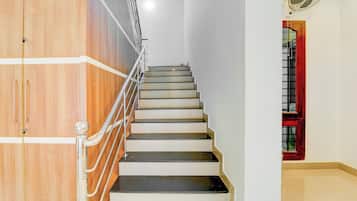 Uma escadaria com uma porta de madeira à esquerda e uma porta com moldura vermelha à direita.
