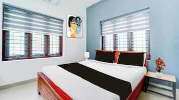 Quarto moderno com uma cama grande, duas janelas com persianas, ar-condicionado fixado na parede e um quadro abstrato emoldurado.