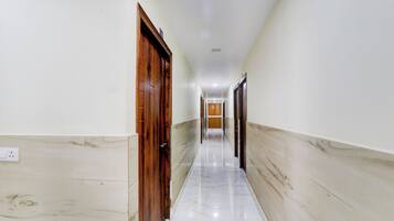 Um corredor com piso de mármore, portas de madeira e um acesso a um quarto com porta de madeira.