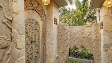 Parede de pedra com esculturas elaboradas e uma porta de madeira com padrões detalhados.