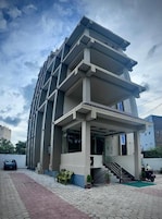 Edifício de vários andares com entrada coberta e escadaria que dá acesso aos pisos superiores.