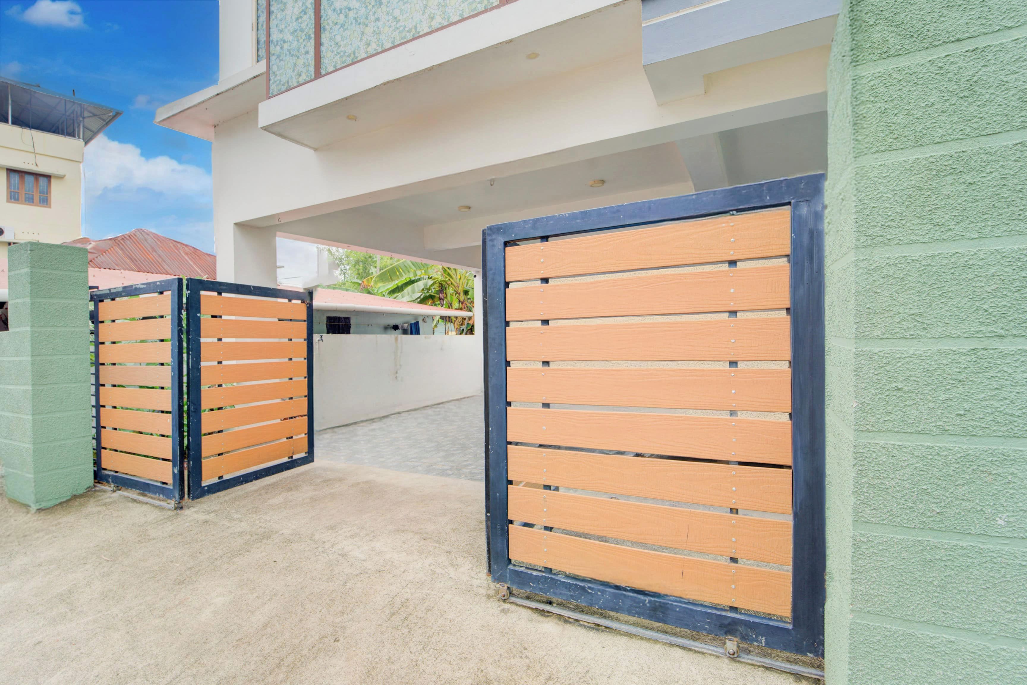 Entrada com portão para um edifício moderno, piso de concreto e céu claro.