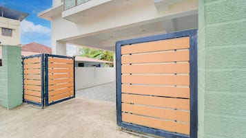 Entrada com portão para um edifício moderno, piso de concreto e céu claro.