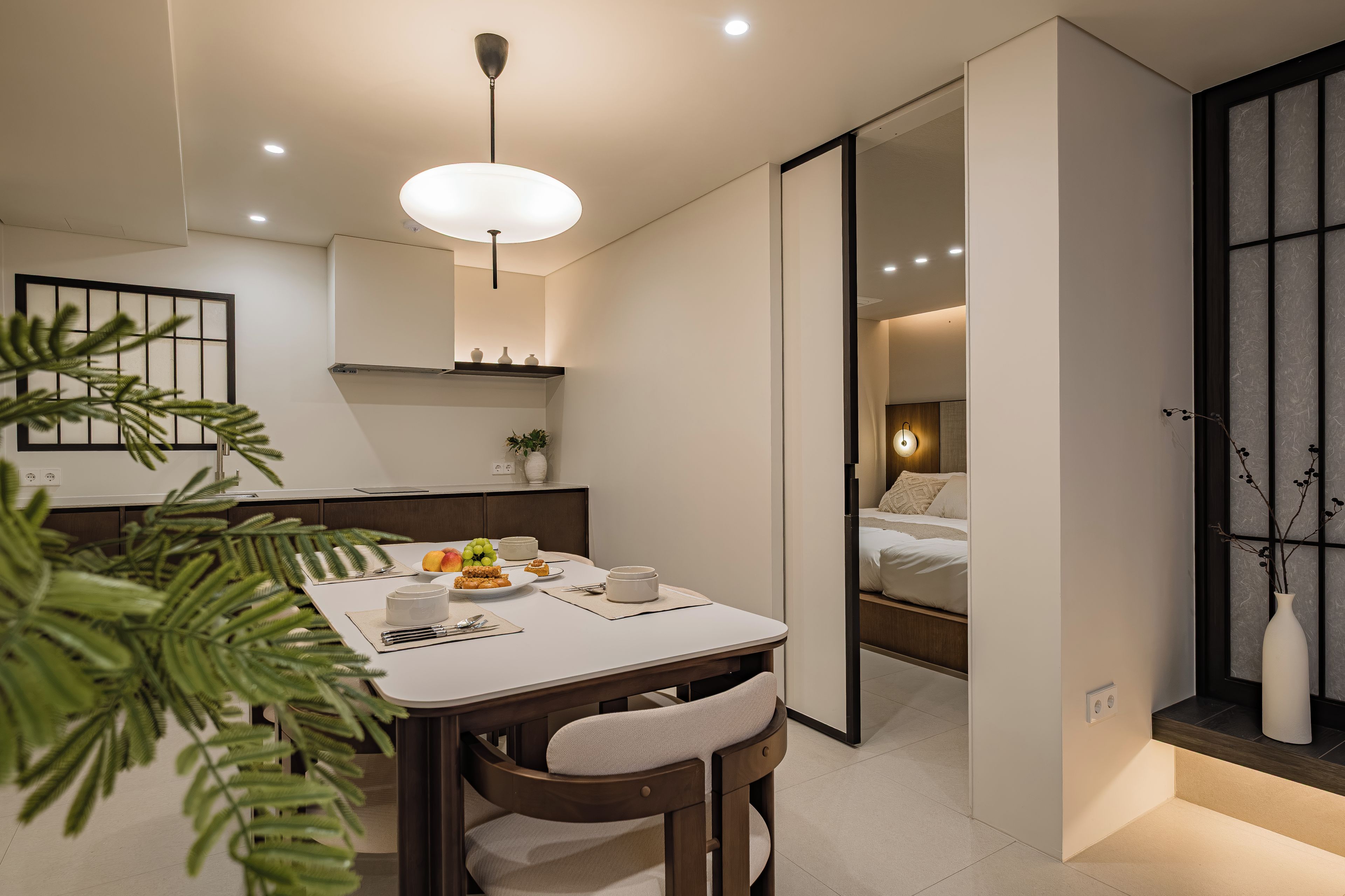 Quarto de hotel moderno com área de refeições, cama e vista da cidade.