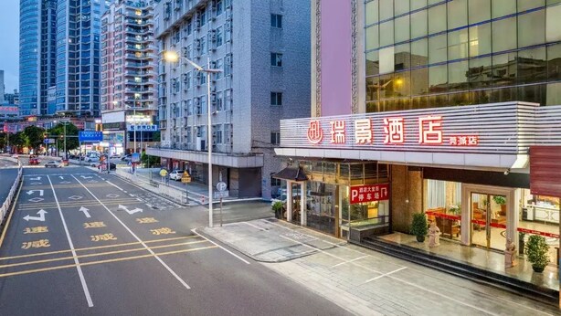 Hotel com fachada moderna, estacionamento e rua com setas indicativas.
