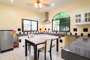 Cozinha com mesa de jantar, cadeiras, geladeira e janela com vista para o verde.