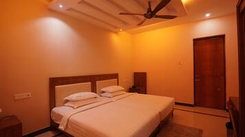 Quarto de hotel com cama, mesas de cabeceira, ventilador de teto e porta.
