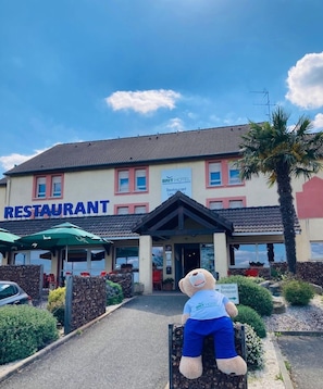 Hotel com restaurante chamado 'BRIT HOTEL' e uma estátua de urso em frente.