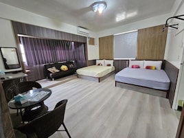 Quarto de hotel com cama, sofá, escrivaninha e uma janela.