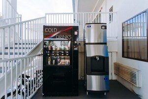 Uma máquina de vendas de bebidas geladas e um bebedouro.