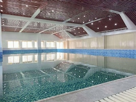 Piscina interna com vista clara para o teto e paredes, e piso azulejado.