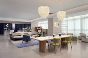 Um hall de hotel moderno com balcão de recepção, área de estar e espaço para refeições.