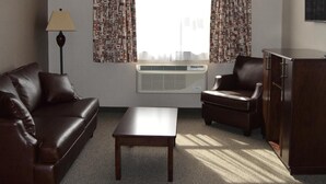 Sala de estar com sofá, poltrona, mesa de centro e janela com cortinas estampadas.