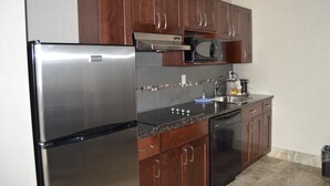 Cozinha com eletrodomésticos de aço inoxidável, armários de madeira e painel de azulejos.