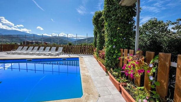 Piscina com espreguiçadeiras e cerca de madeira com plantas trepadoras.