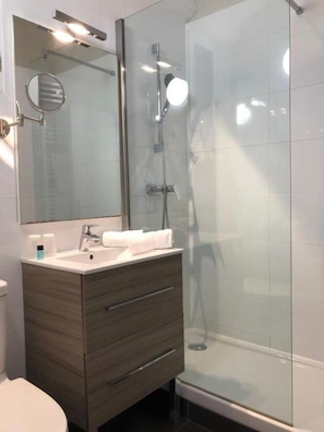 Um banheiro moderno com box de vidro, pia com espelho e vaso sanitário.