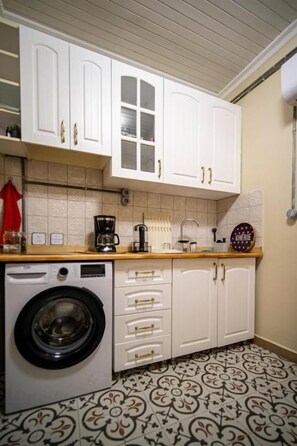 Uma cozinha compacta com armários brancos, máquina de lavar e piso estampado.