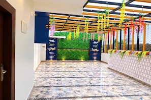 Um corredor com piso estampado, parede verde com jardim vertical e teto com plantas penduradas.