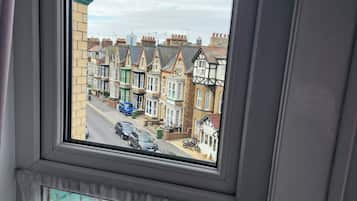Janela com vista para casas em socalcos e carros estacionados.