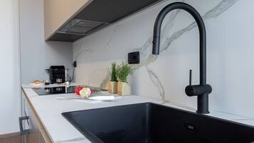 Cozinha moderna com pia preta, painel de mármore branco e coifa embutida.