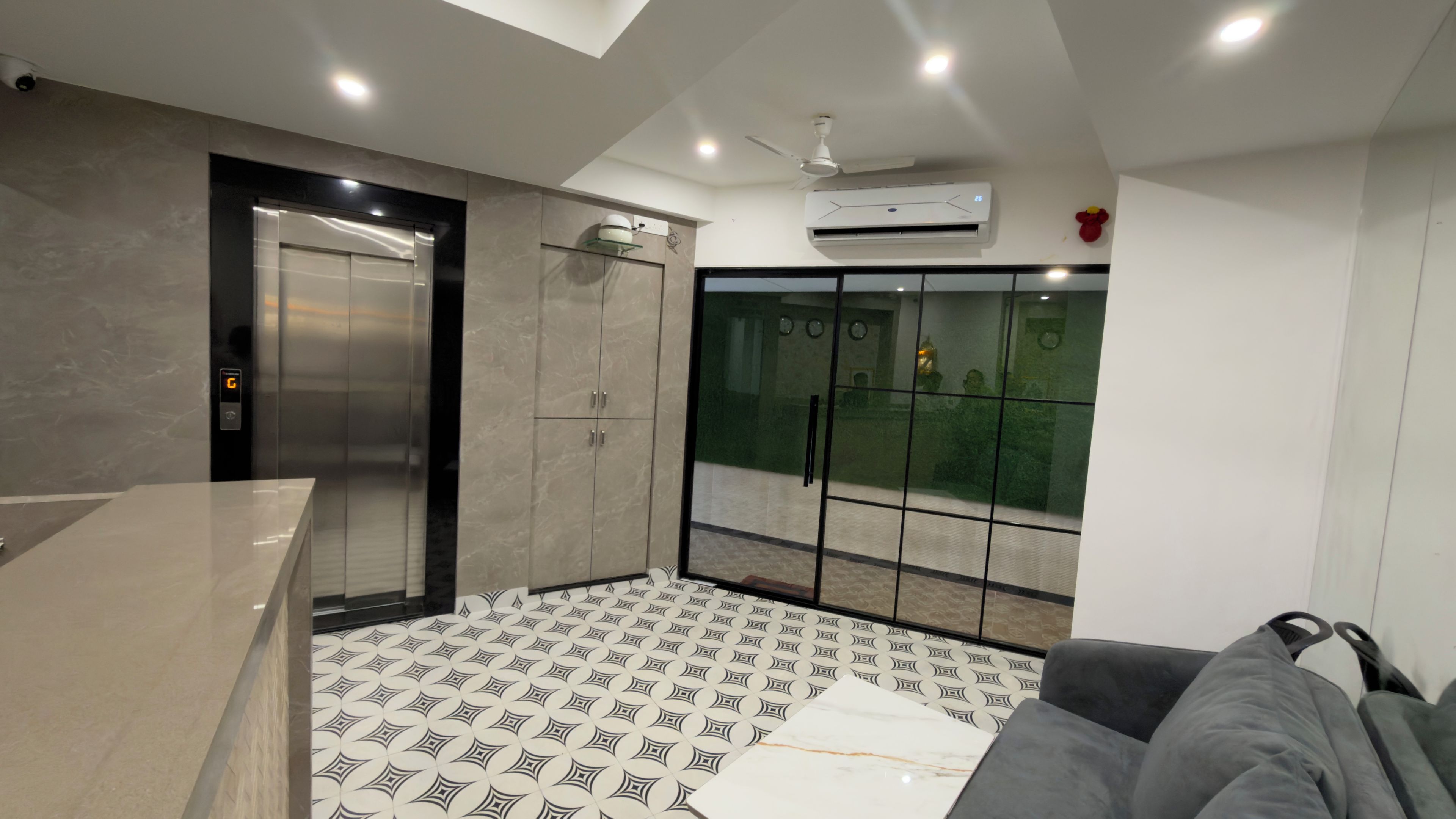 Interior moderno com piso estampado, elevador embutido e porta de vidro que dá para uma varanda.