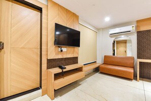 Uma sala de estar moderna com televisão de tela plana fixada numa parede de madeira, um sofá de couro e um sistema de entretenimento embutido.