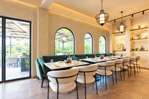 Um restaurante com área de assentos em cabines verdes, mesas brancas e cadeiras pretas.