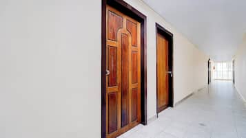 Corredor com duas portas de madeira e piso ladrilhado.
