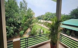 Uma varanda com vista para uma paisagem verde, um caminho e um edifício com telhado verde.