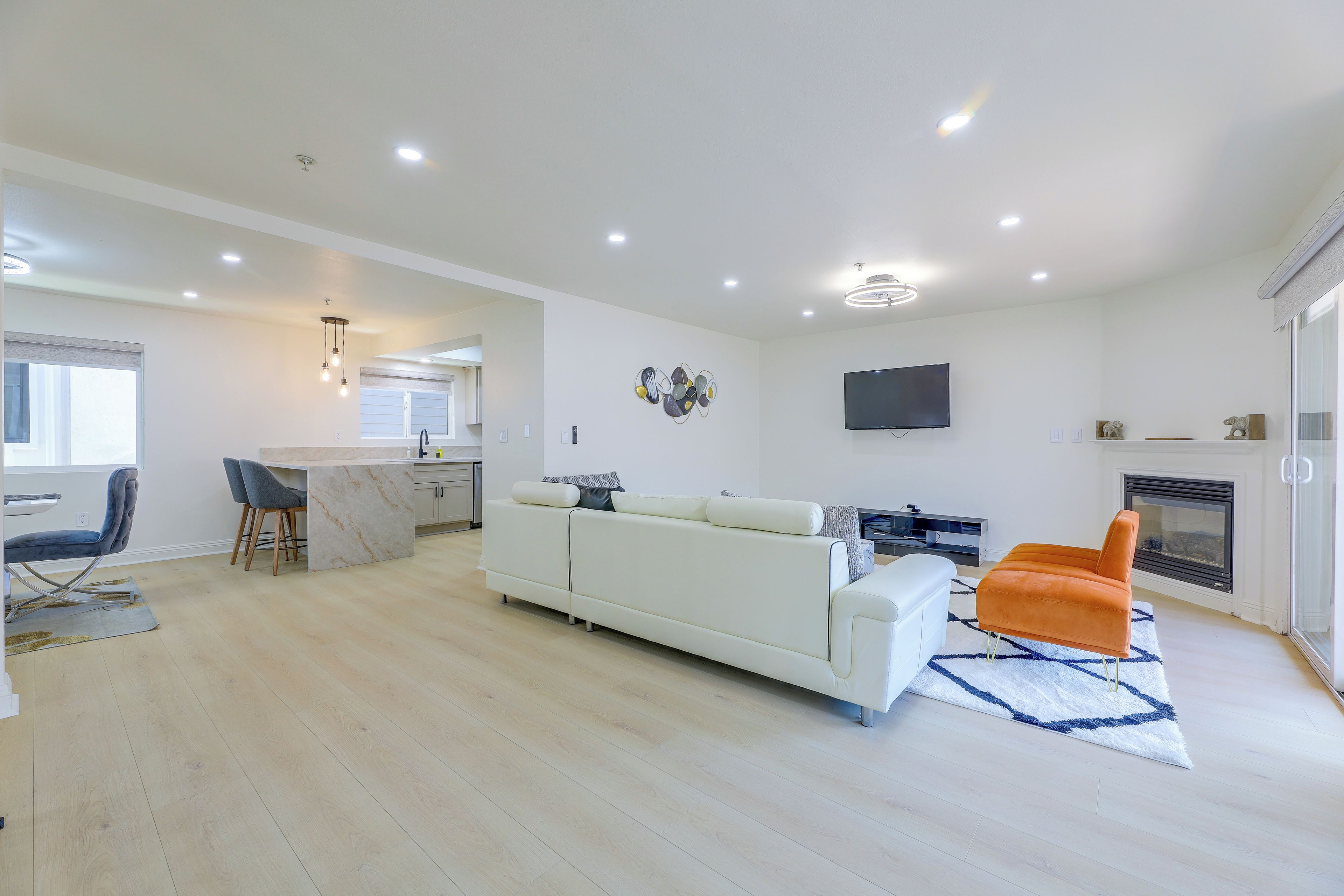 Uma sala de estar moderna com sofá branco, TV fixada na parede e lareira.