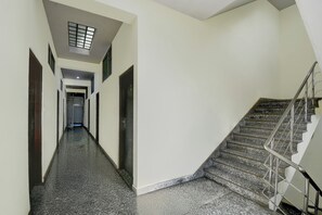 Um corredor com escada à direita, dando acesso a um andar superior.