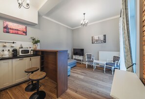 Um espaço de estar compacto com cozinha compacta, área de estar e televisão.