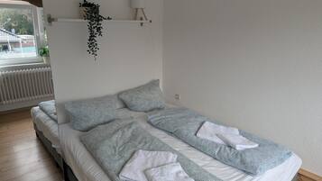 Quarto com cama, almofadas, planta pendurada e radiador.