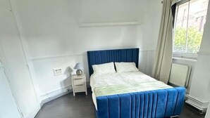 Quarto com cama, mesa de cabeceira e janela.