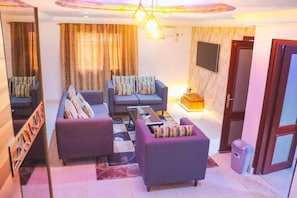 Sala de estar com sofá, mesa de centro e televisão na parede.