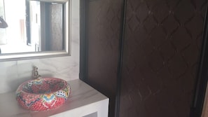 Casa de banho com lavatório de mármore, espelho e porta escura com padrão.