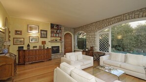 Sala de estar com lareira, sofás brancos, mesa de centro e parede de pedra.
