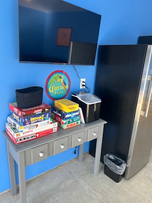 Quarto com parede azul, televisão de tela plana fixada acima de um console cinza e geladeira preta.