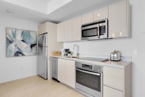 Uma cozinha moderna com eletrodomésticos de aço inoxidável, micro-ondas, torradeira e lava-louças.