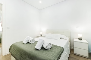 Quarto de hotel com cama, duas mesas de cabeceira e um criado-mudo.