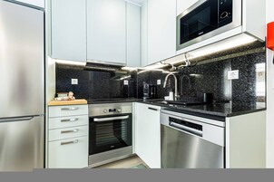 Cozinha moderna com eletrodomésticos de aço inoxidável, micro-ondas e lava-louças.