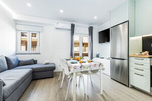 Um apartamento moderno com área de jantar, cozinha compacta e sofá cinzento.