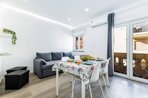 Um espaço de estar moderno com área de jantar, sofá cinzento e varanda com vista.