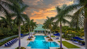 Área de piscina do resort com espreguiçadeiras e palmeiras.