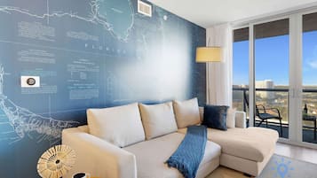 Uma sala de estar moderna com um grande mapa na parede, um sofá, uma mesa de centro e vista para a cidade pela varanda.