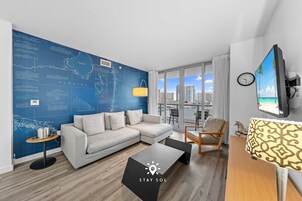 Uma sala de estar moderna com uma janela ampla, um sofá, uma mesa de centro e um mural com mapa.