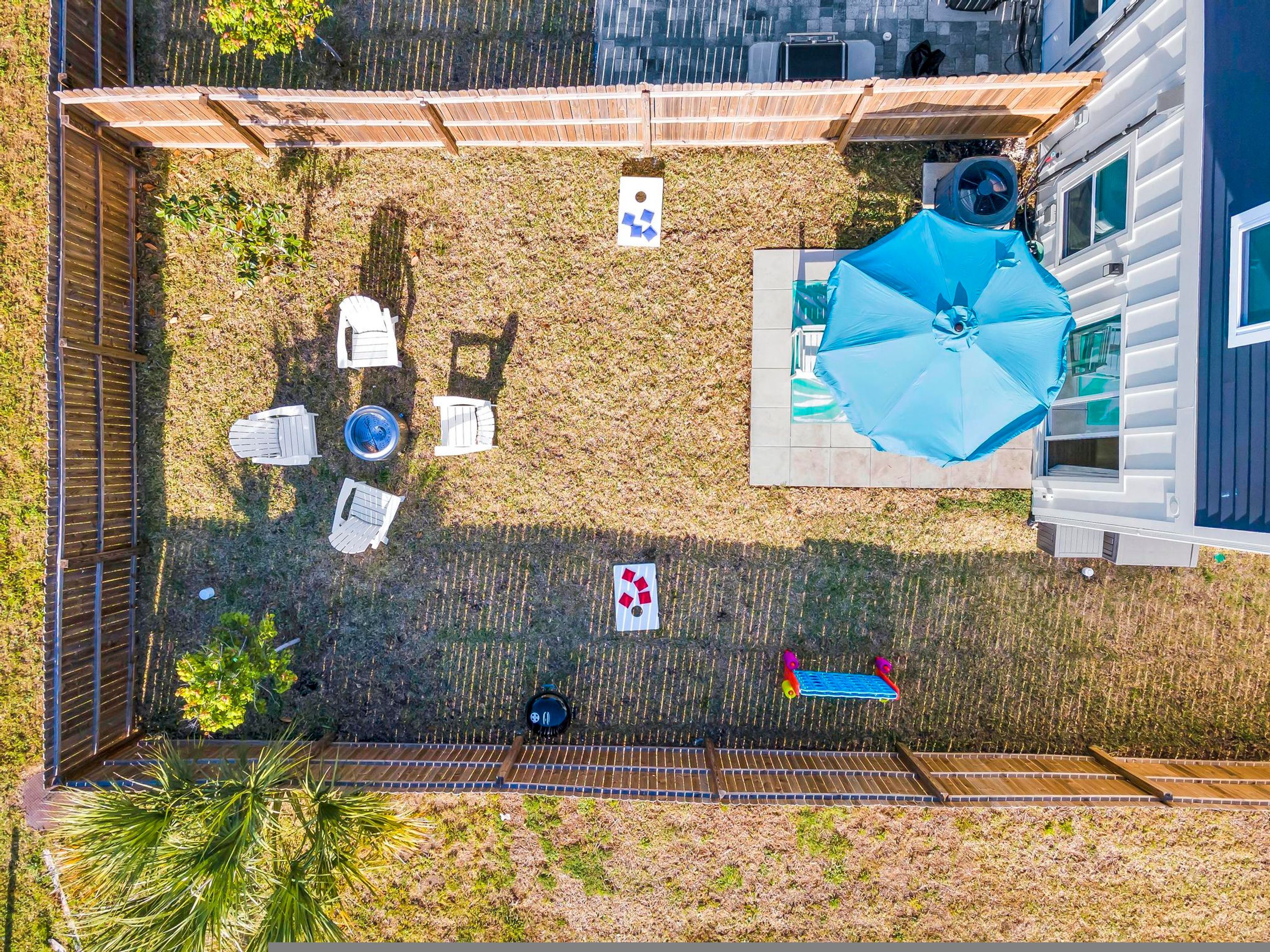 Vista aérea de um quintal com área de pátio, mobiliário de jardim e piscina.