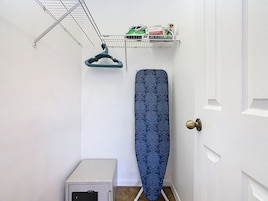 Quarto pequeno com porta e armário brancos, e um varal fixado na parede com roupas.