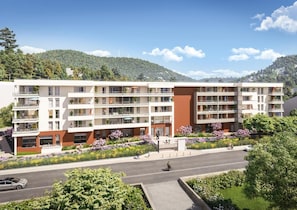 Um hotel com vários andares, varandas, um jardim paisagístico e vista para uma paisagem montanhosa.