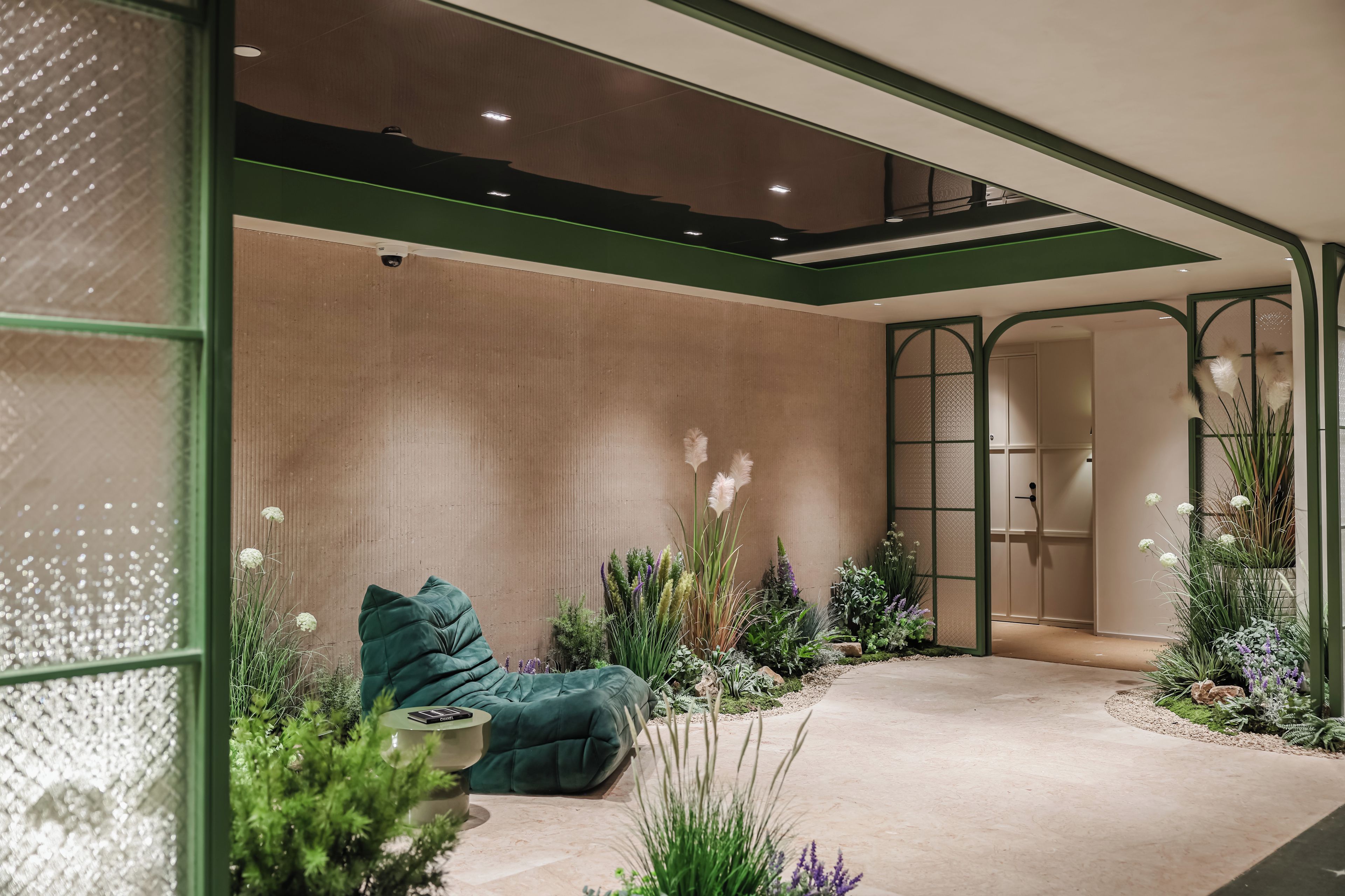 Um interior moderno com área de estar, um sofá estofado verde e diversas plantas.